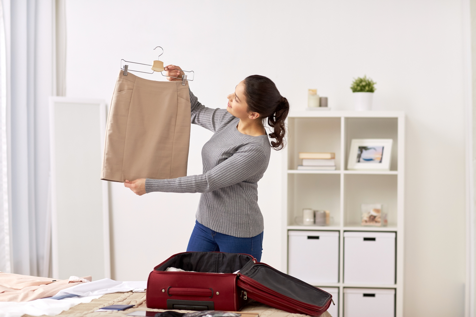woman packing travel bag at home or hotel room - Coworker Mag