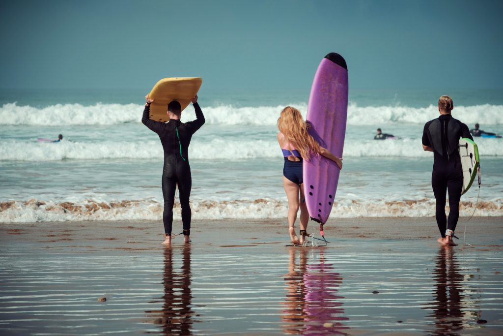 Surfer friends on a beach with a surfing boards - Coworker Mag